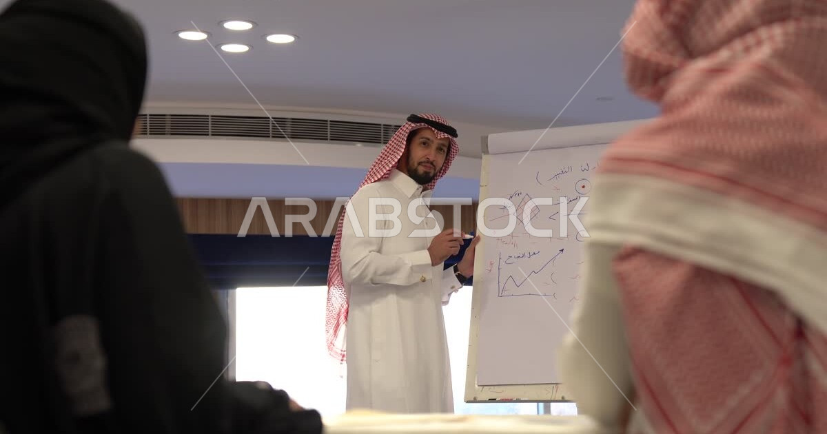 A Saudi Arabian trainer explains to Saudi Gulf trainees on a whiteboard ...
