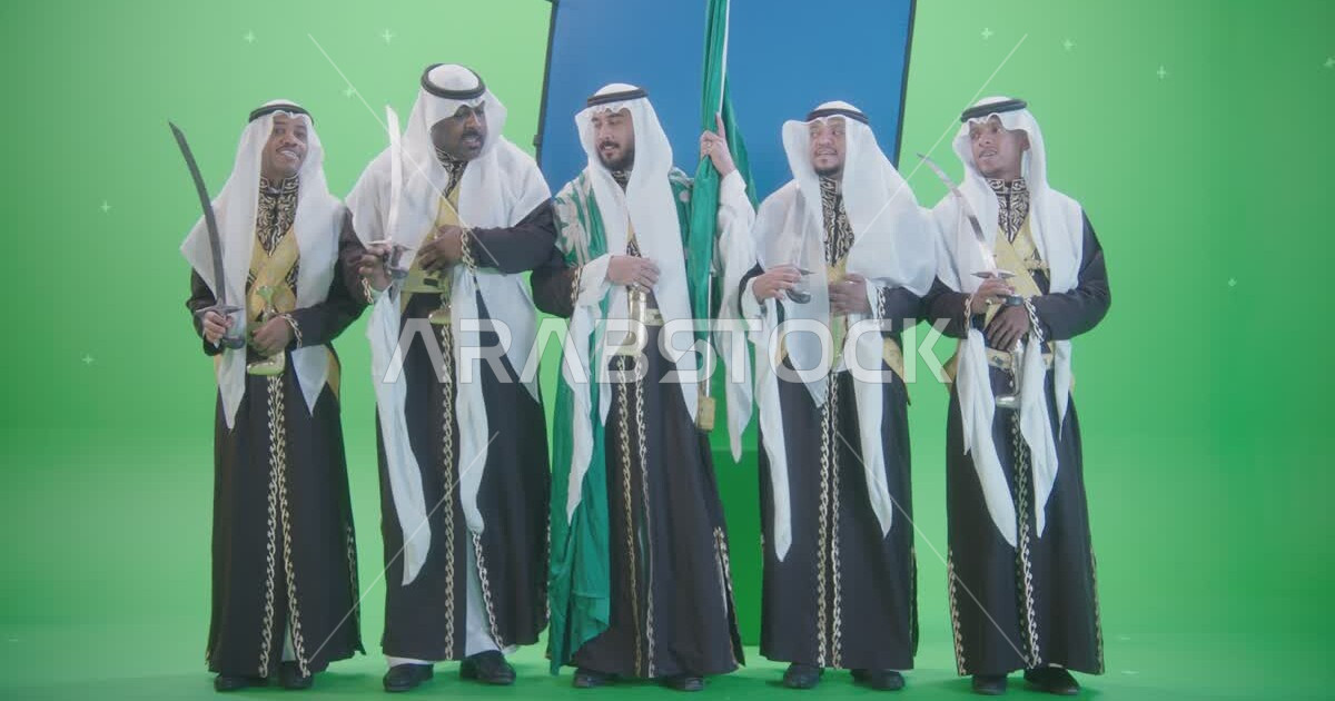 A Saudi Ardah with the Saudi flag performing the Saudi Ardah on a green ...