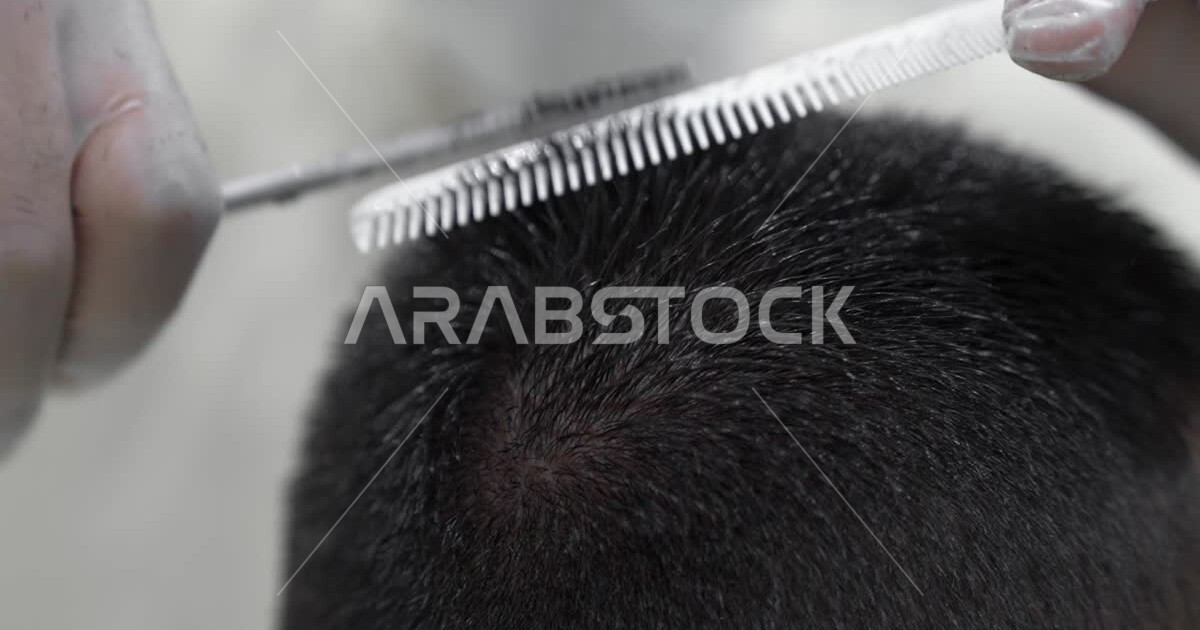 A Saudi Arabian Gulf man visits a barber shop. The barber uses the ...
