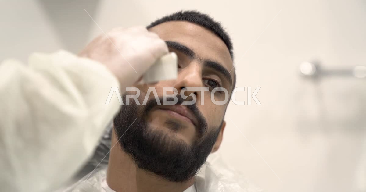 A Saudi Arabian Gulf man visits a hairdressing salon. The barber takes ...