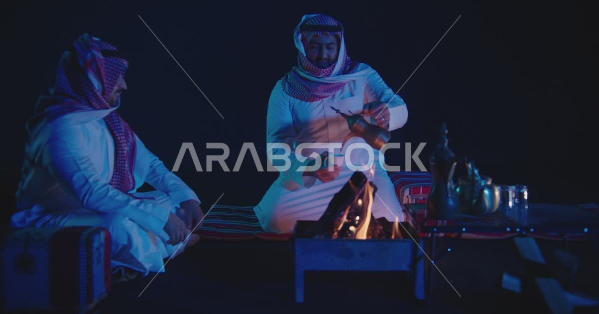 Arabic coffee dallah, two young Saudi Gulf Arab men enjoying spending ...