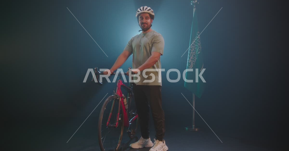 Standing next to the Saudi flag, a Saudi Gulf Arab man holding a ...