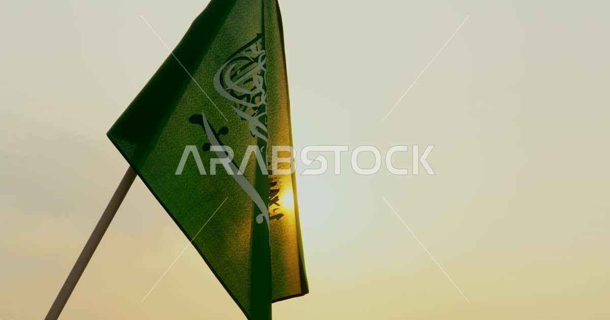 A close-up of the green flag of the Kingdom of Saudi Arabia in the sky ...