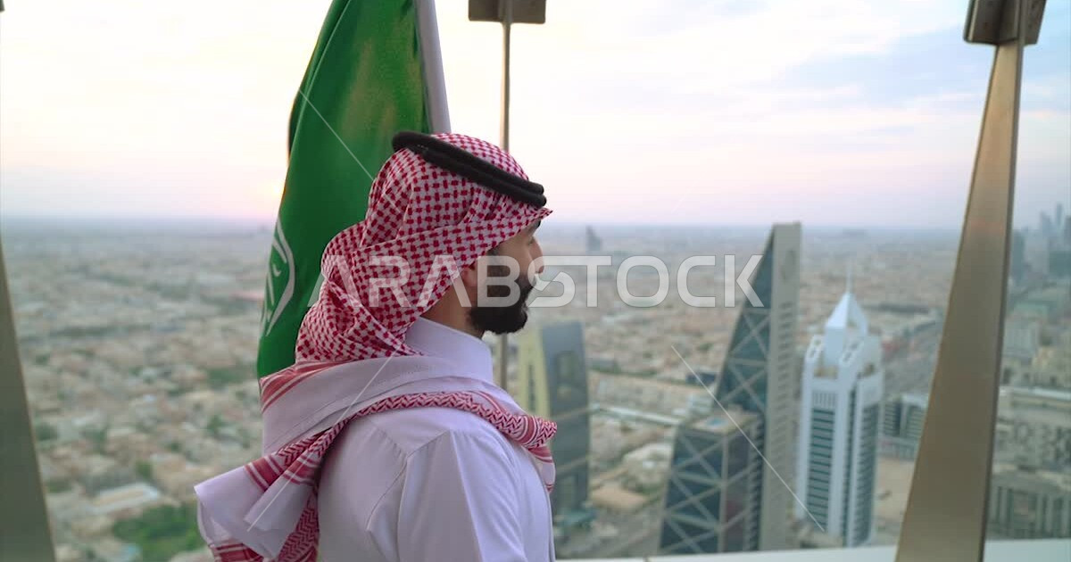 A young Saudi Gulf man in traditional Saudi dress, holding in his hand ...