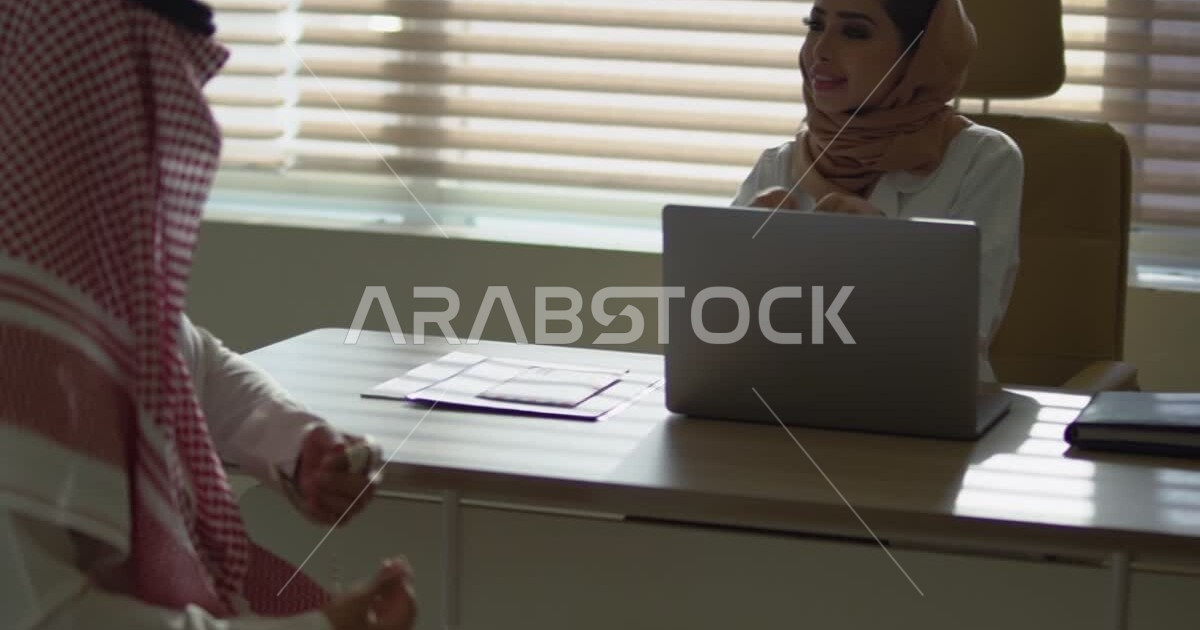 A Saudi Arabian Gulf doctor wearing a medical coat and sitting in her ...