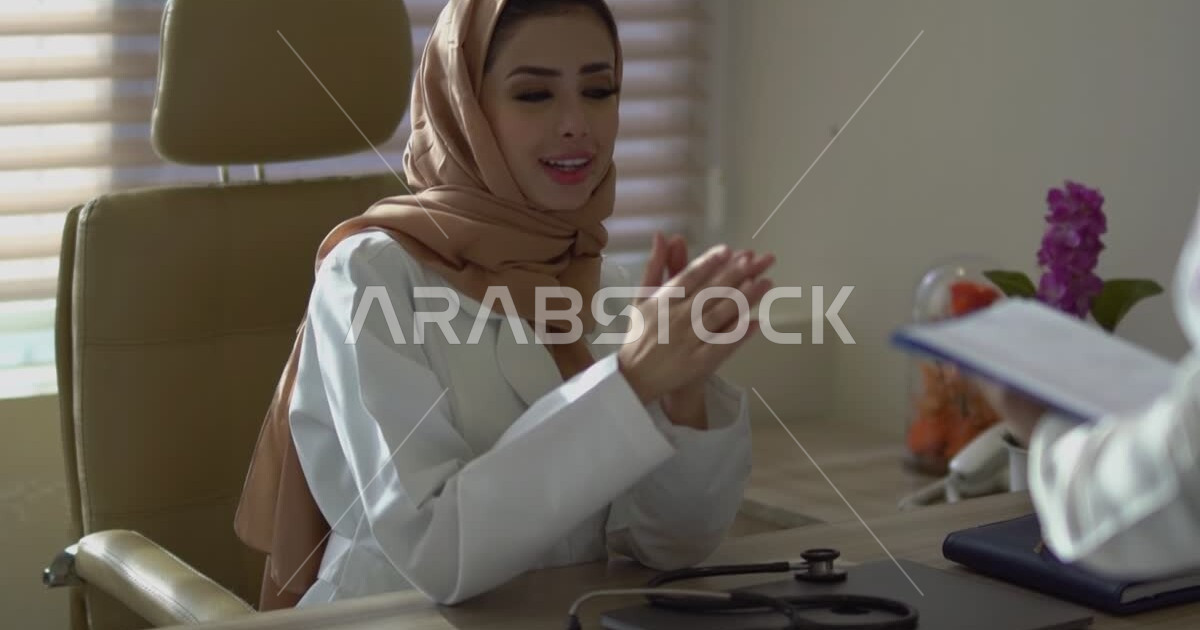 A Saudi Arabian Gulf doctor wearing a medical coat and sitting in her ...