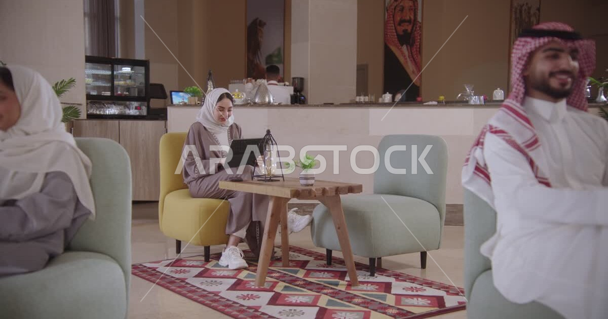 Studying and working remotely, a young Saudi Arab Gulf woman sits in a ...