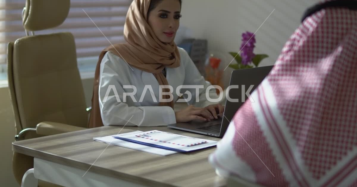 A Saudi Arabian Gulf doctor wearing a medical coat and sitting in her ...