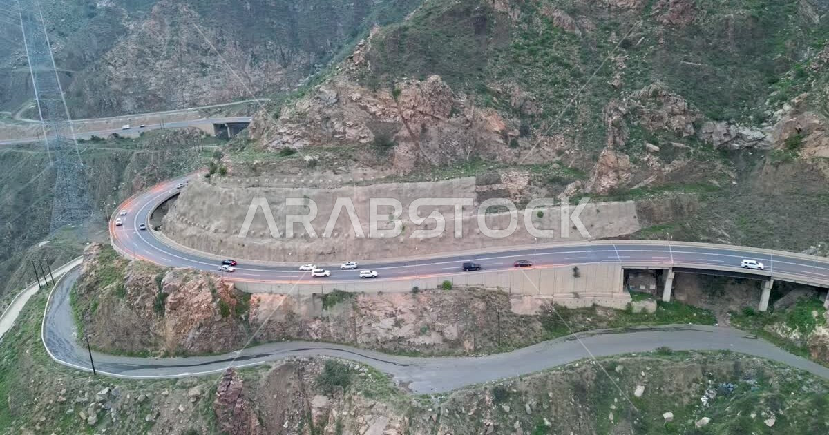 Car traffic on mountainous asphalt roads between the peaks and ...