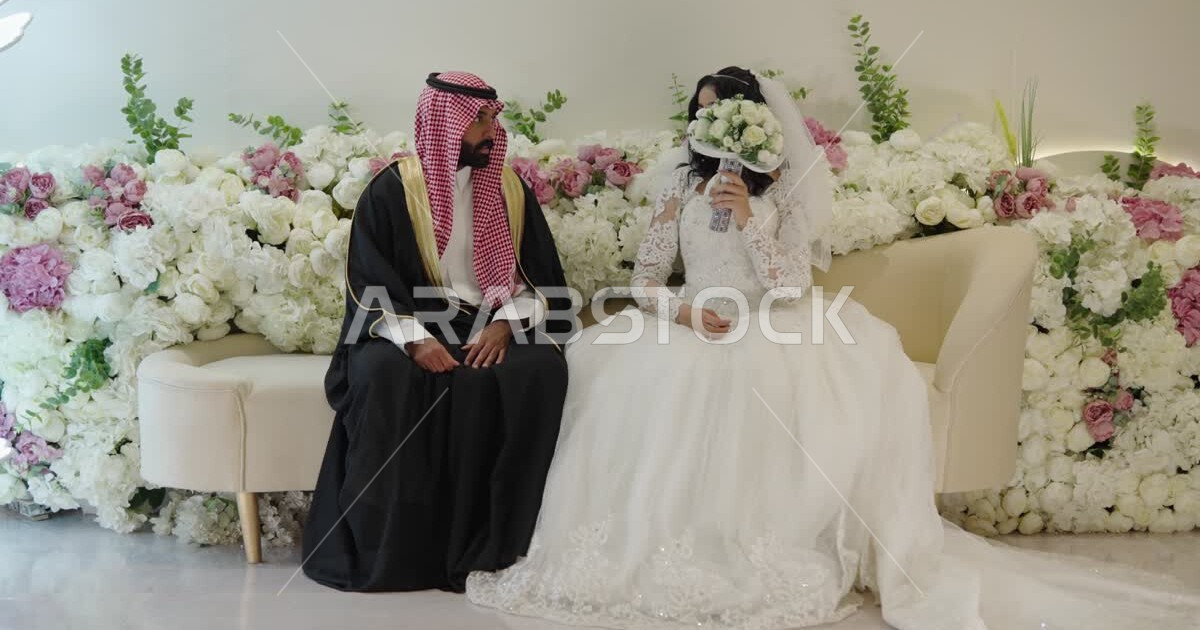 A Saudi Arabian Gulf bride wearing a white wedding suit, hiding her ...