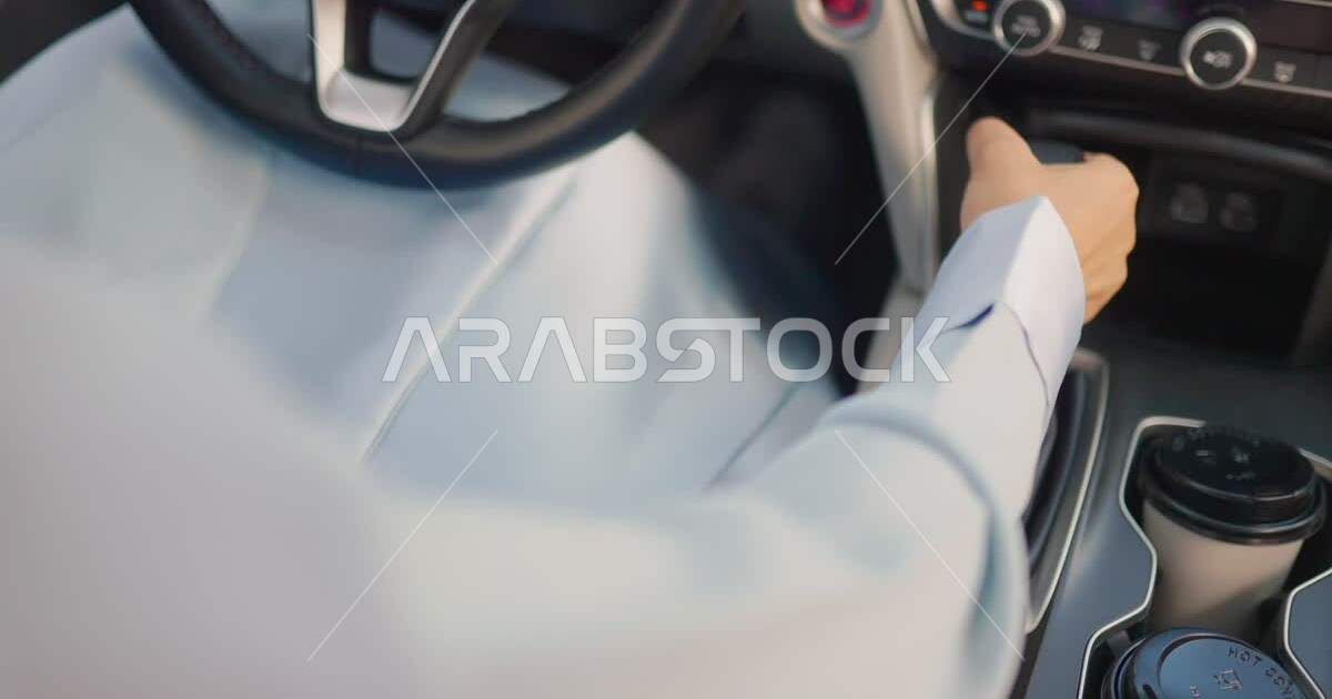 A veiled Saudi Arabian Gulf Arab driver uses a car gearbox to move the ...