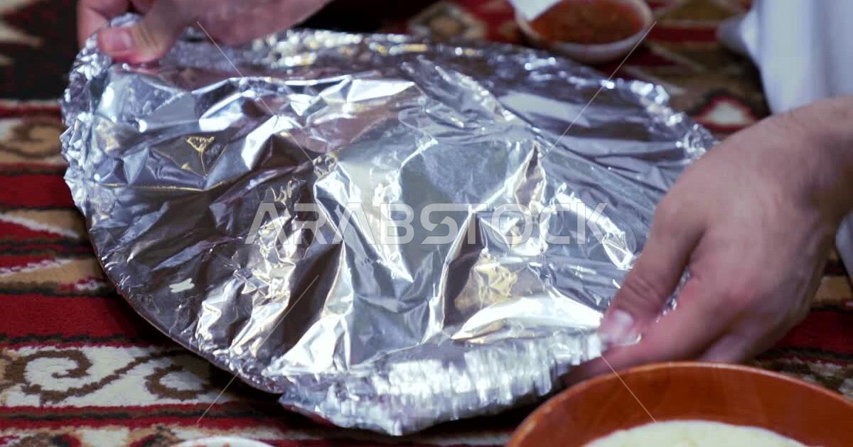 A Saudi Arabian Gulf man at the dining table, eating by hand, sitting ...