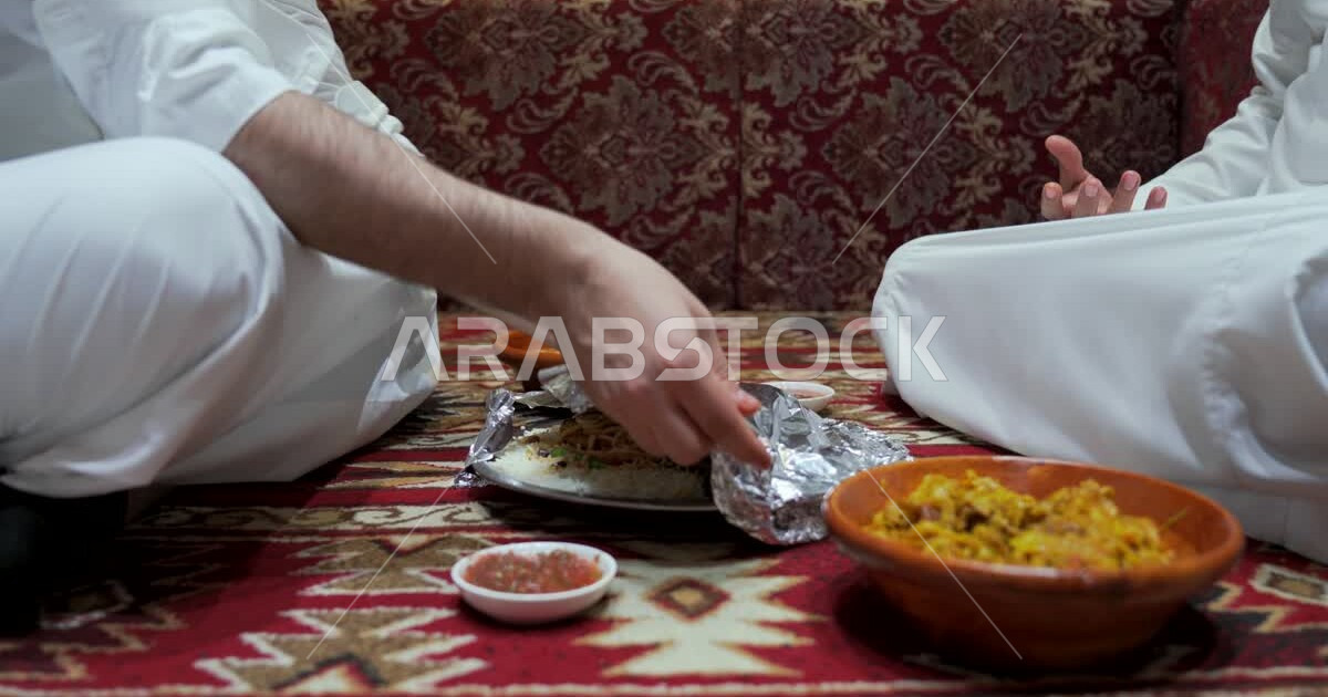 Two young Saudi Arabian Gulf men gathered at the dining table, Ramadan ...