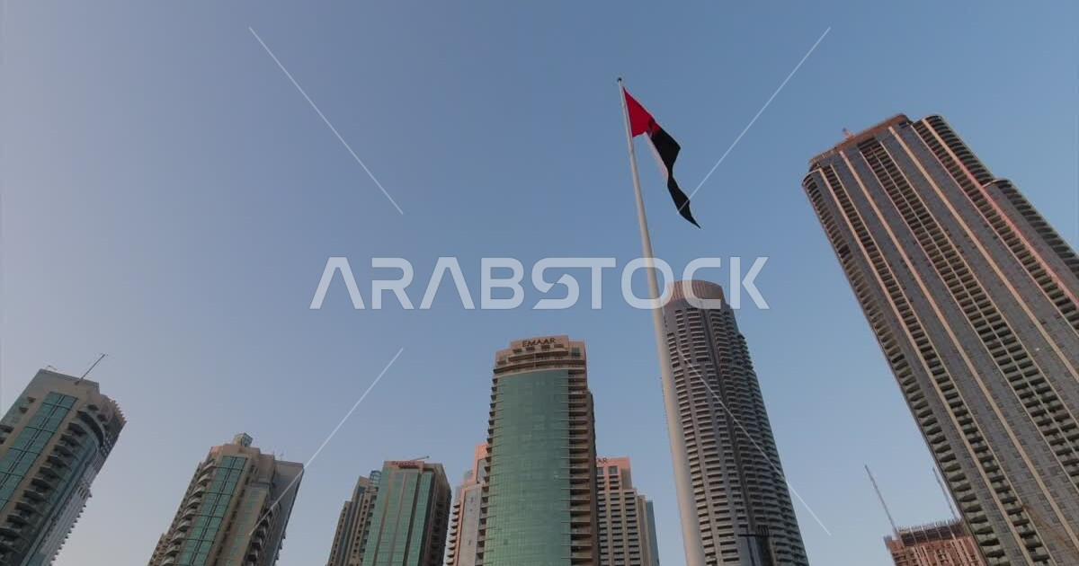 The flag of the United Arab Emirates fluttering in the sky in front of ...