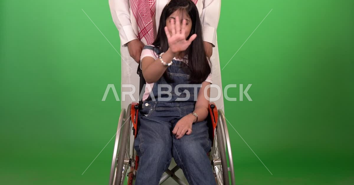 Portrait of a Saudi Arabian girl in a wheelchair with her father, with ...