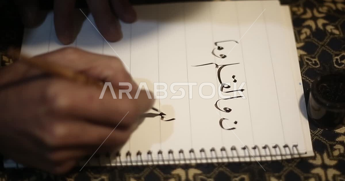 A close-up of the hand of a Saudi Arabian Gulf calligrapher drawing a ...