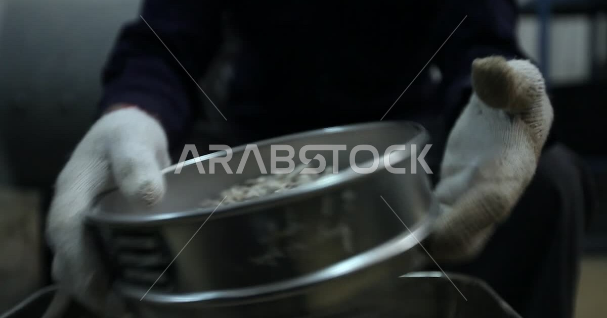 A close-up photo of a worker filtering asphalt to repair and pave ...