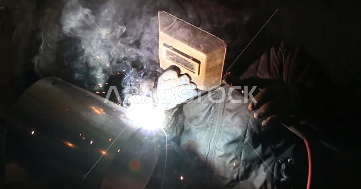 A close-up photo of a Saudi Gulf Arab blacksmith wearing protective ...
