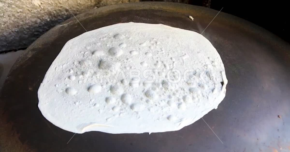 Making flatbread from wheat flour, a close-up of the hand of a Saudi ...