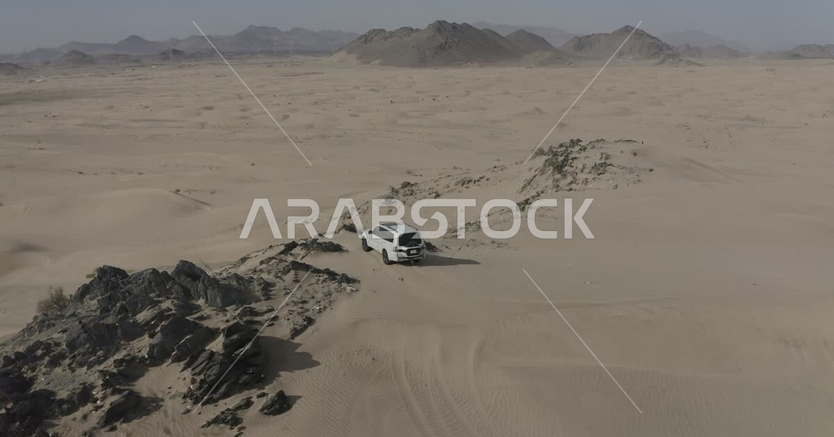 Driving a four-wheel drive vehicle through the dunes and soft golden ...