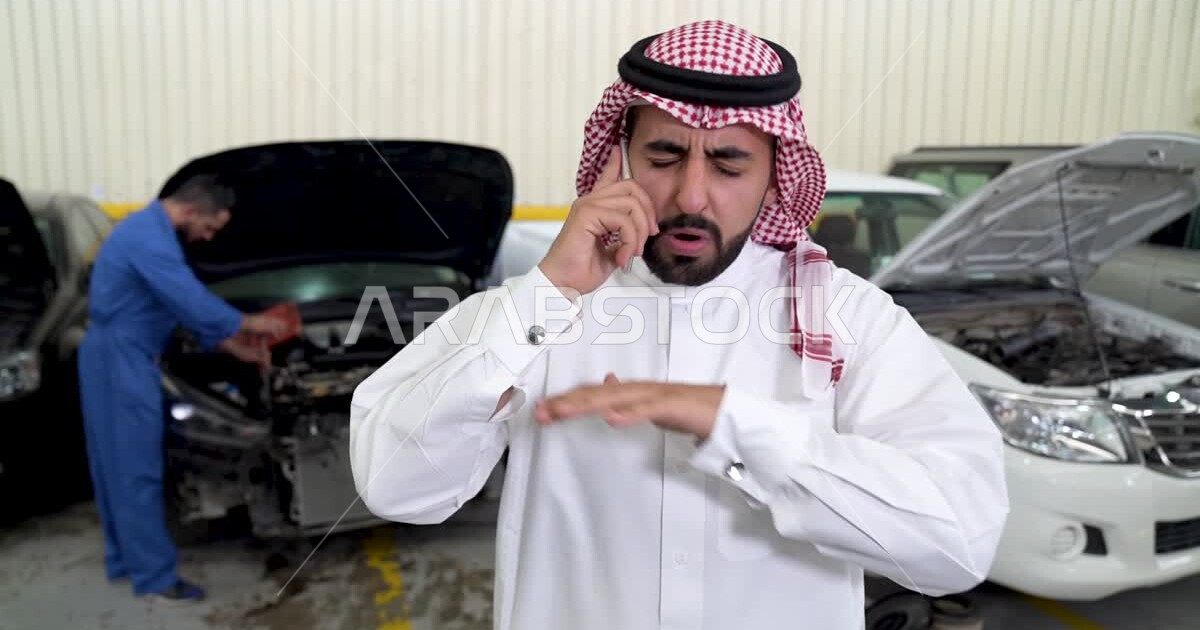 A Saudi Arabian man inside the car workshop, uses his mobile phone ...