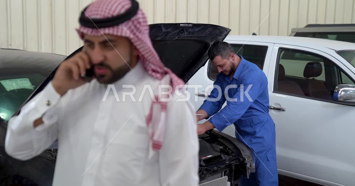A Saudi Arabian man inside the car workshop, uses his mobile phone ...