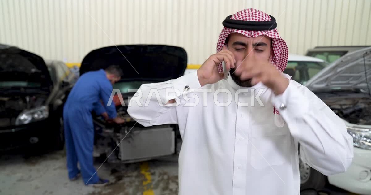 A Saudi Arabian man inside the car workshop, uses his mobile phone ...