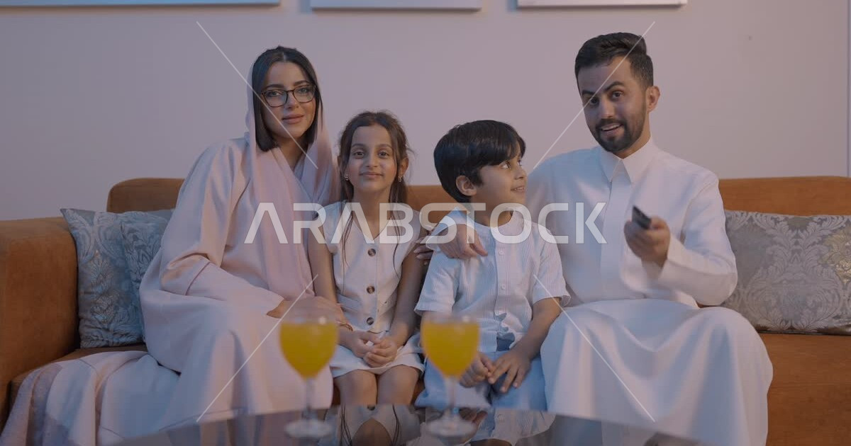 A Saudi Gulf Arab couple watching TV and eating popcorn and juice with ...