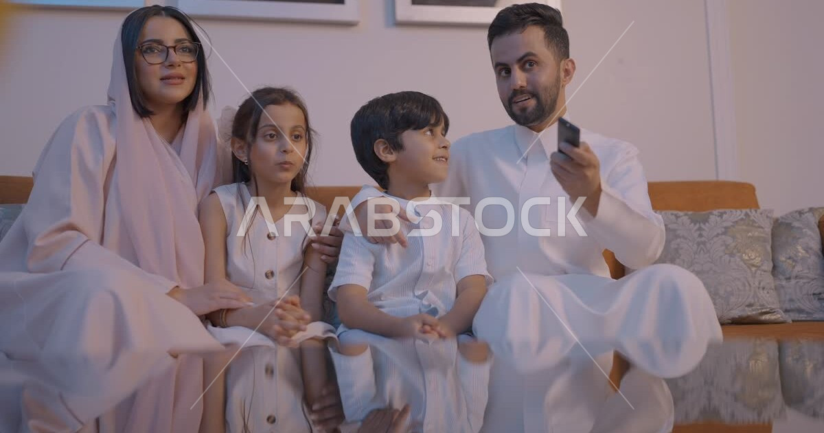 A Saudi Gulf Arab couple watching TV and eating popcorn and juice with ...