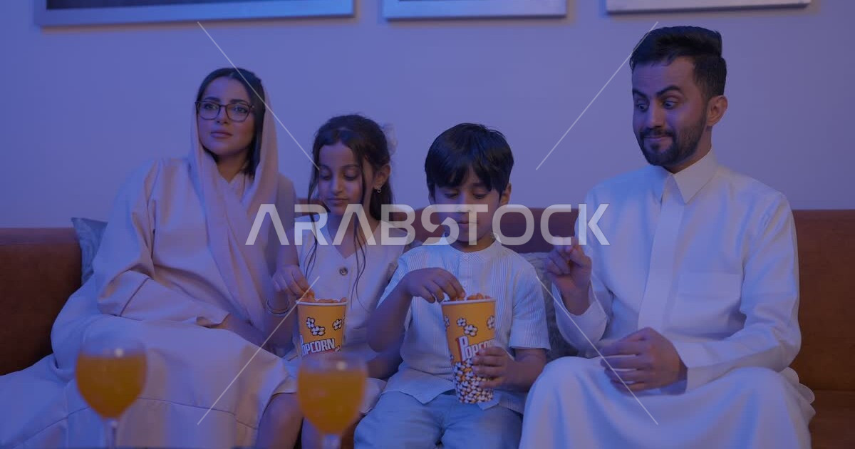 Gestures of integration and focus, a Saudi Gulf Arab couple watching TV ...