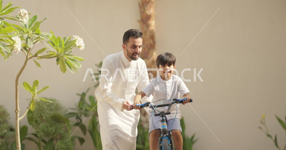 Practicing bicycle riding, a Saudi Gulf Arab boy riding a bicycle with ...