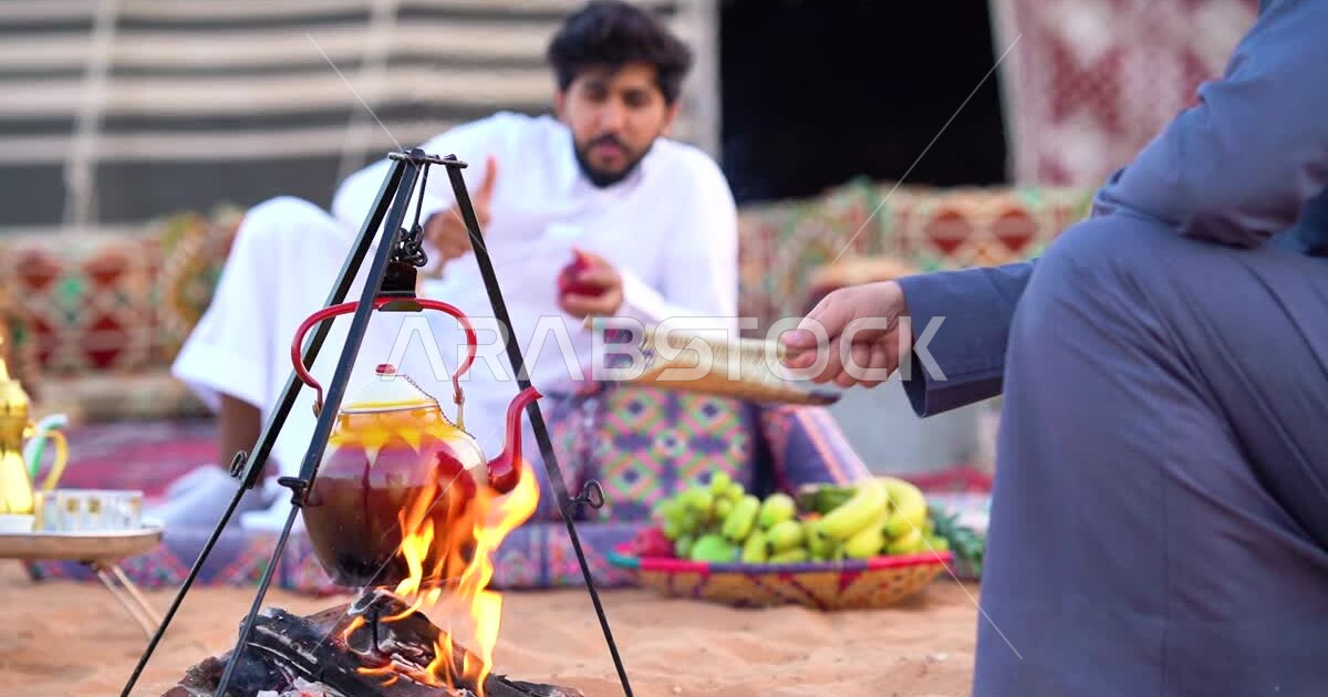 Saudi youth in a popular session on land, a Saudi man uses a hand fan ...