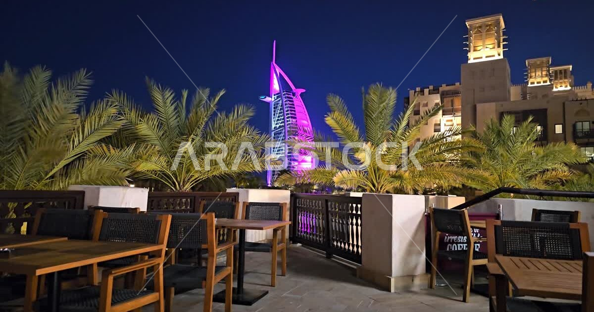 Open cafe overlooking the Burj Al Arab building illuminated at night ...