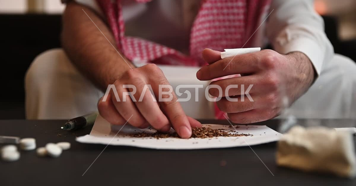 A young Saudi Arab smoker, wrapping cigarettes with his hands inside ...