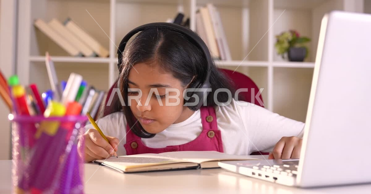 A Saudi Arabian student doing homework at home, studying through an ...