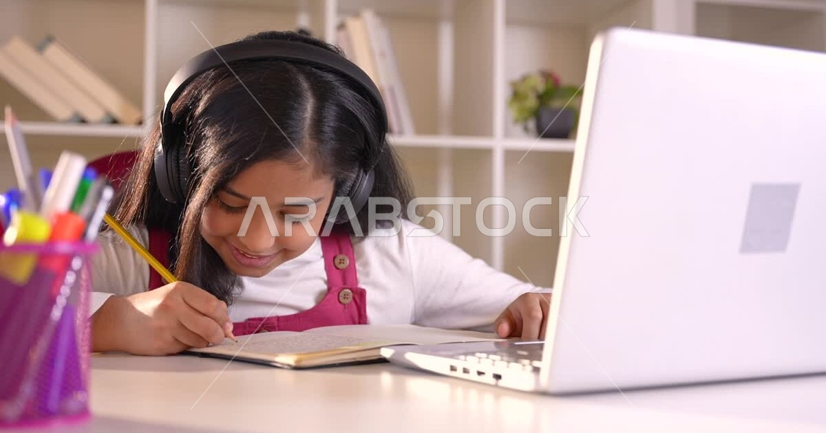 A Saudi Arabian student doing homework at home, studying through an ...