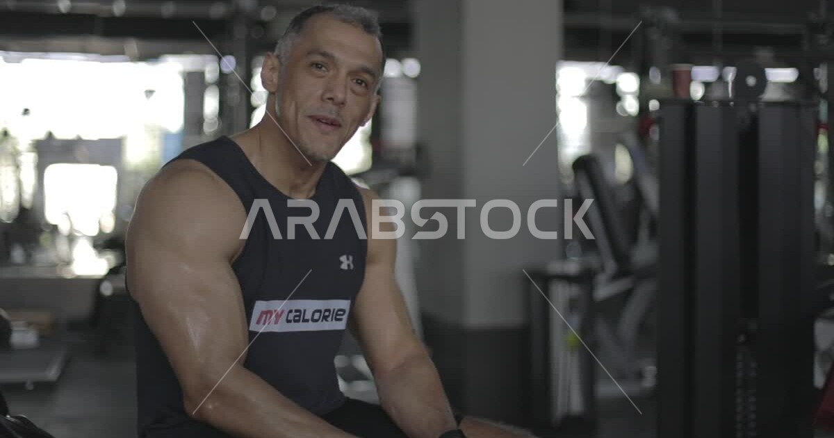 Using a towel to dry sweat after exercise, Saudi Arabian Gulf man ...
