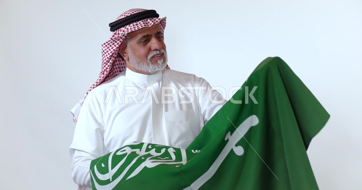 Portrait of an old Saudi Arab man holding the flag of Saudi Arabia and ...