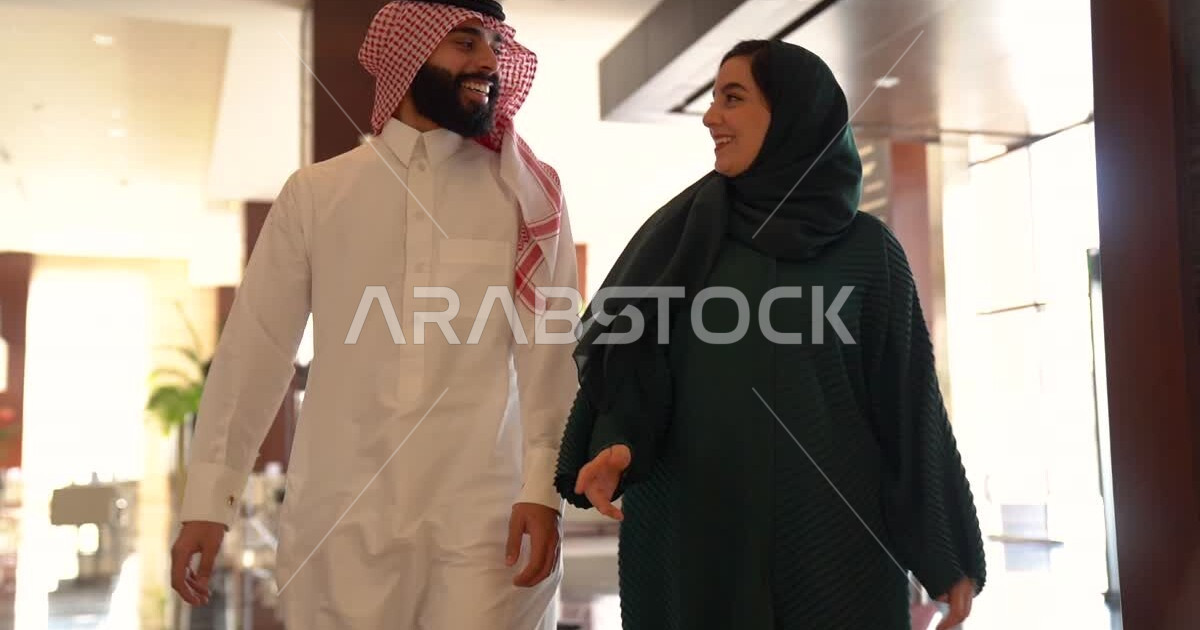 A Saudi couple smiling tourists and entering the tourist hotel to spend ...