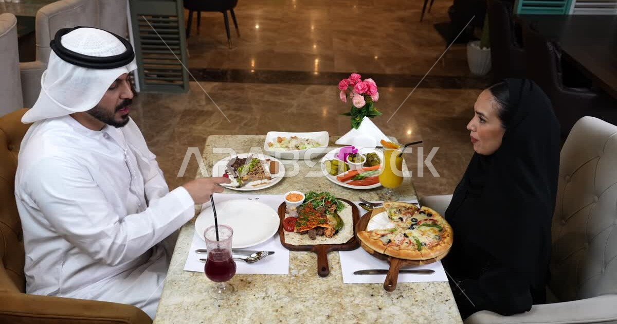 Variety of delicious foods, side view of an Emirati Gulf Arab couple ...