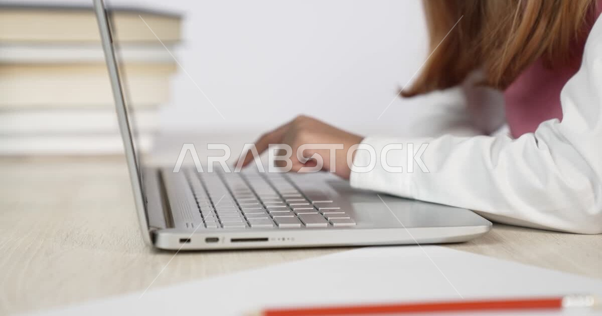 A Saudi Arabian Gulf schoolgirl wearing a school uniform, sitting in ...
