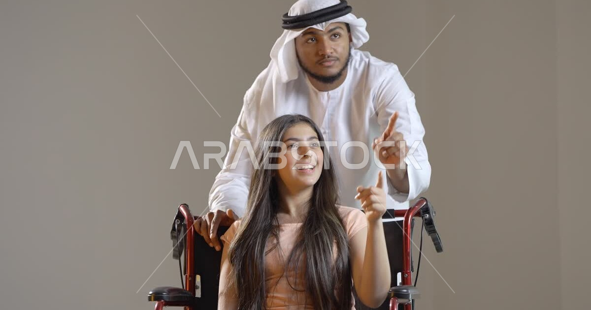 Pointing to something, a disabled Arab Gulf Emirati girl wearing casual ...
