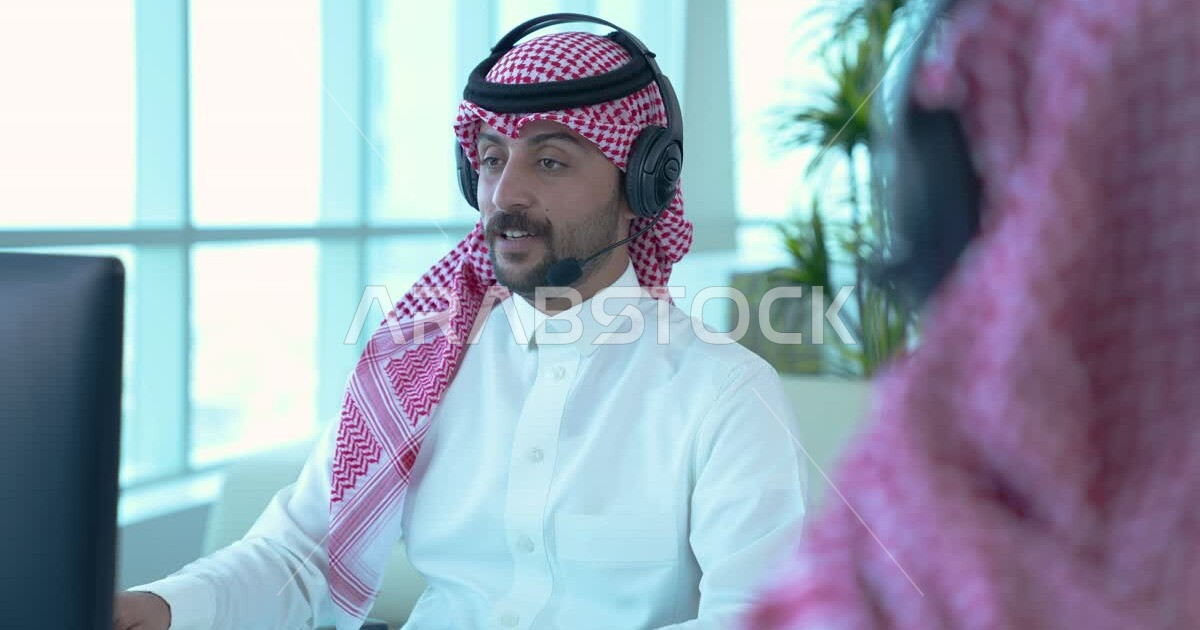 A smiling Saudi Arabian Gulf employee while talking to a customer in ...