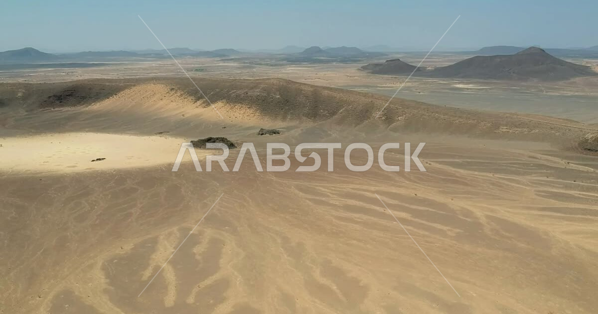 Camera drone flies backward over a crater in the Harrat Kishb volcanic ...