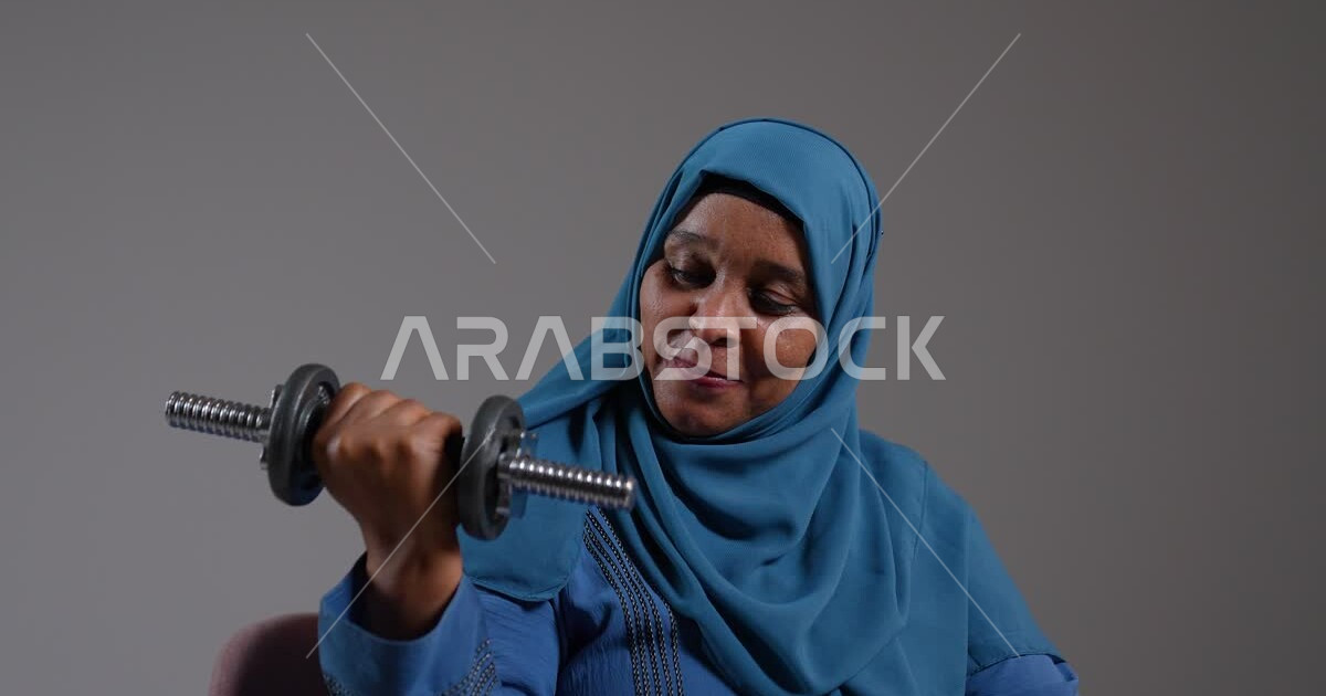 Exercising and lifting heavy weights, close-up of a veiled Saudi ...