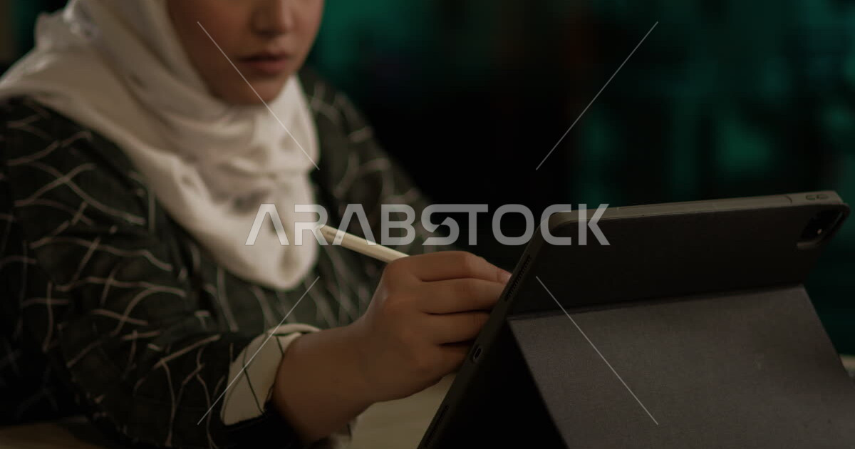 A Saudi Arabian Gulf business woman, using a tablet and a laptop to ...