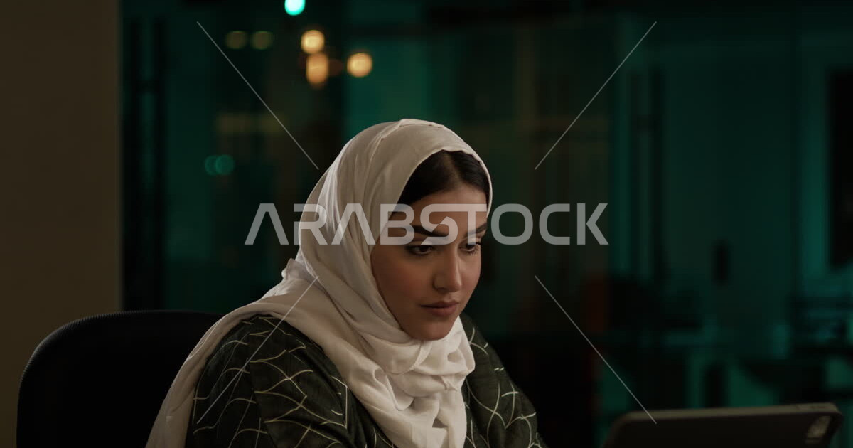 A Saudi Arabian Gulf business woman at her workplace, using tablets and ...