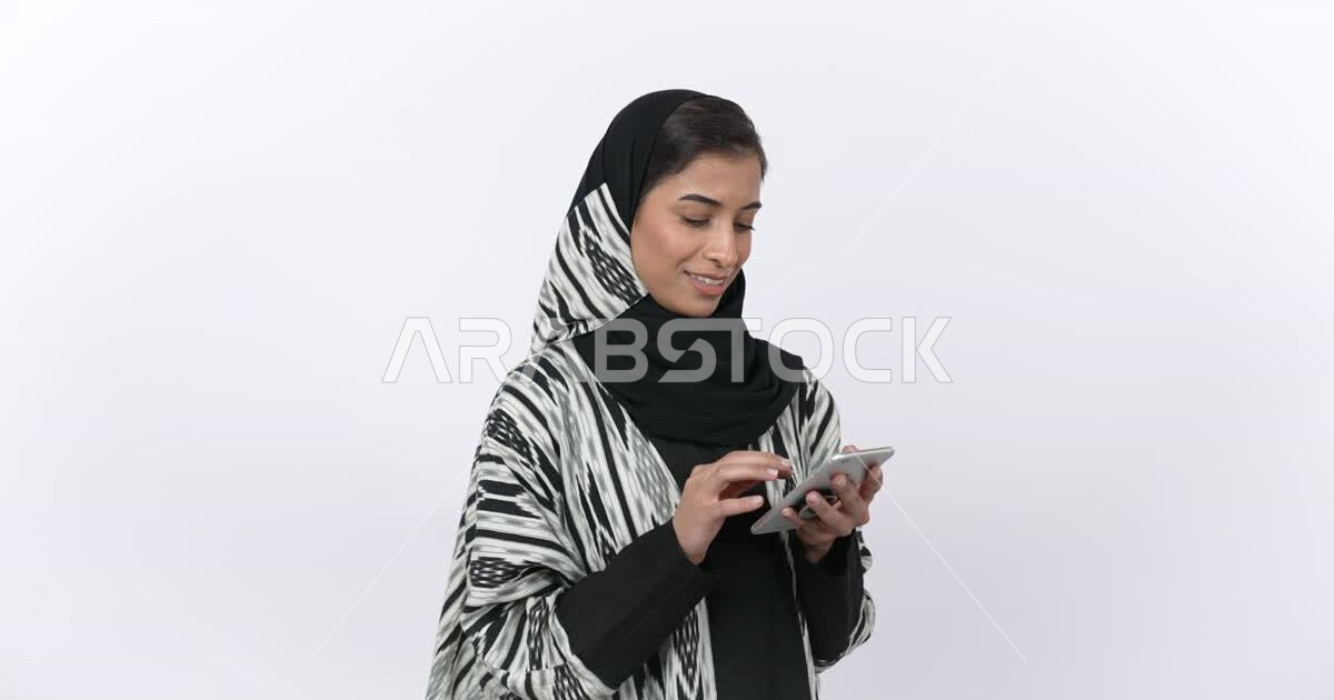 A Saudi Arabian Gulf business woman, holding a mobile phone, making a ...