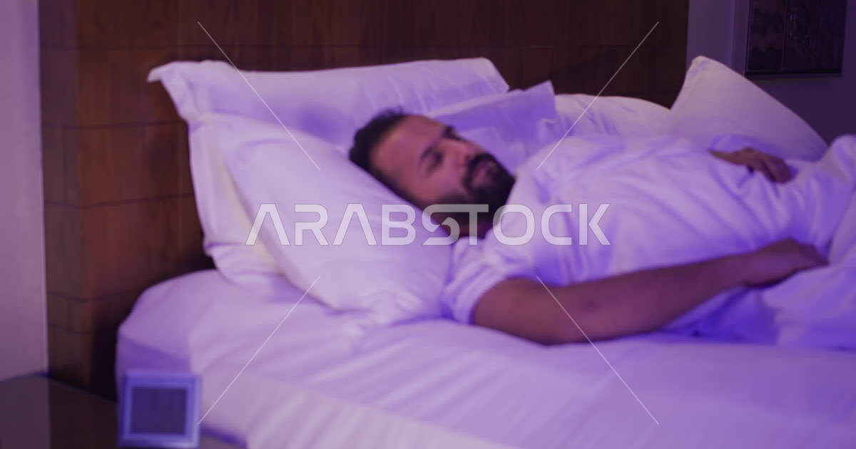 A Saudi Arabian Gulf man sleeps in a fresh and comfortable bed on a ...