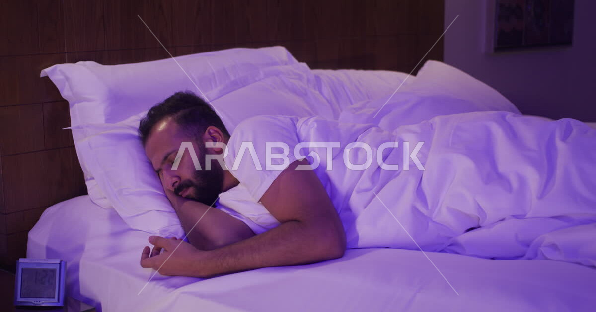 A Saudi Arabian Gulf man sleeps in a fresh and comfortable bed on a ...